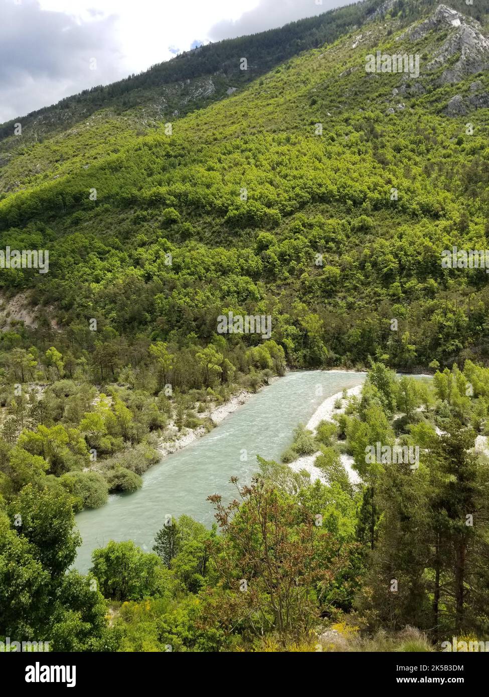 A vertical shot of a river flowing through mountains covered with ...