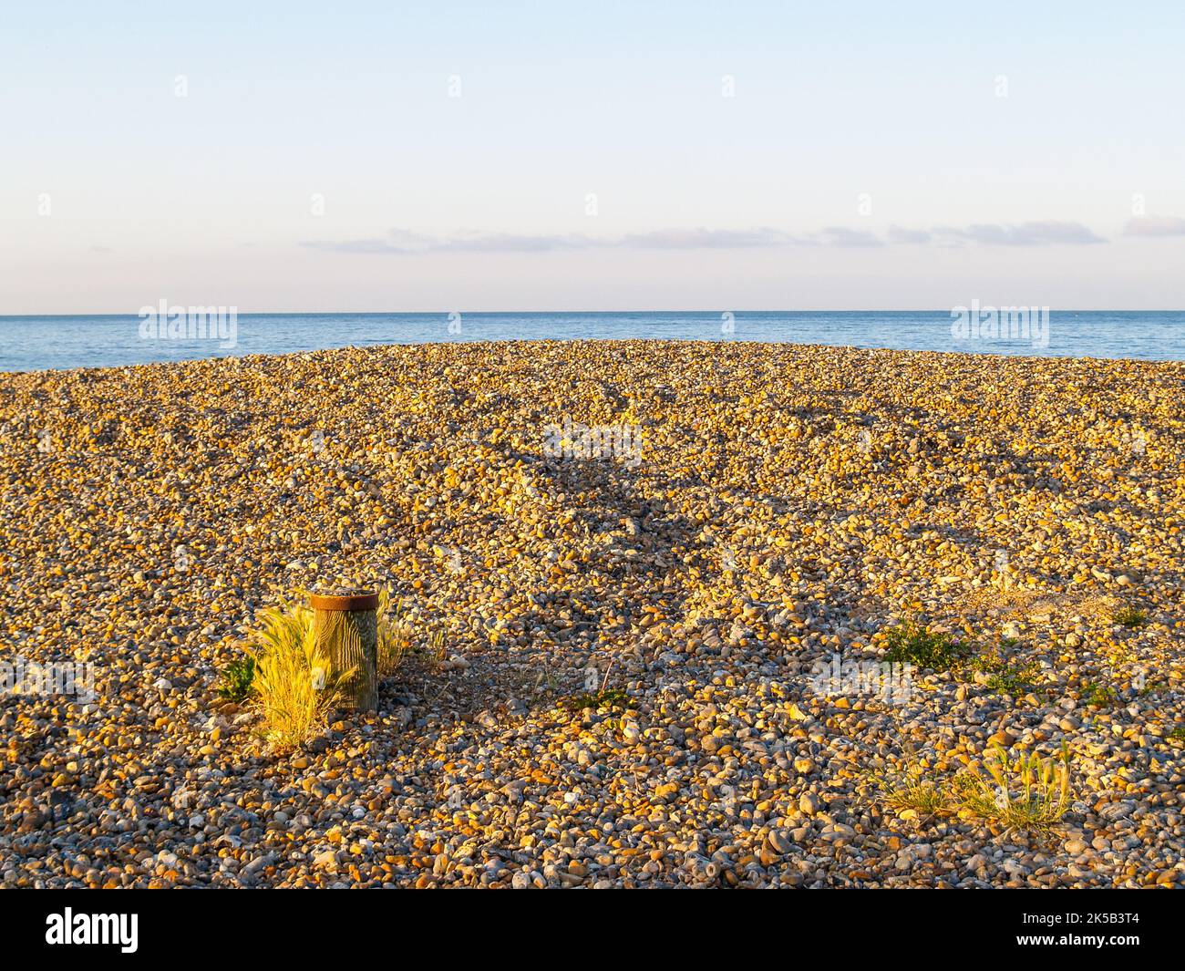 Stony beach at sunrise with area orange pebbles leading to water and ...
