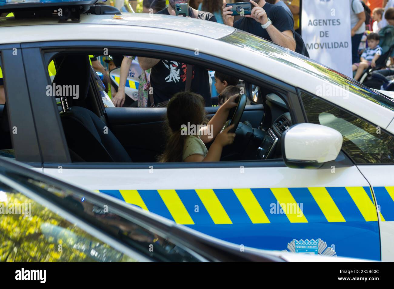 A little girl inside a police car being trained for basic traffic rules ...