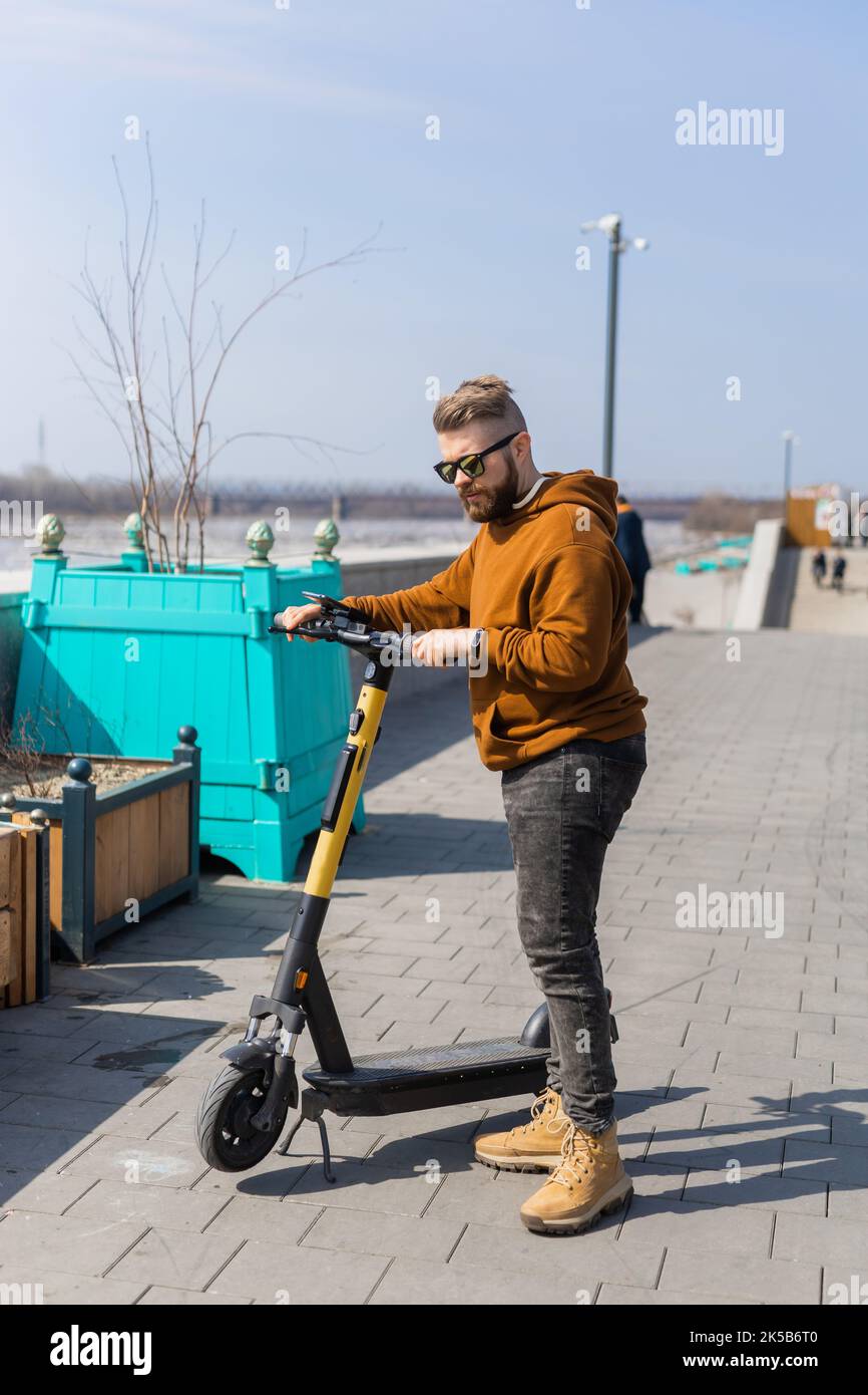 Handsome guy man riding on electric urban modern scooter. Eco transport ...