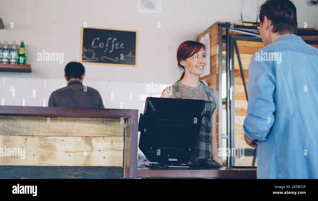 Busy work day at cozy coffeehouse with customer standing at counter ...