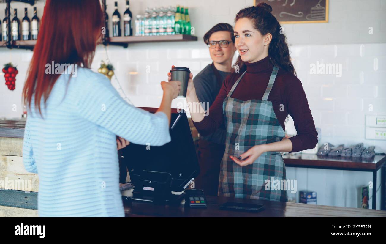Young female customer purchasing takeout coffee in modern coffee shop ...
