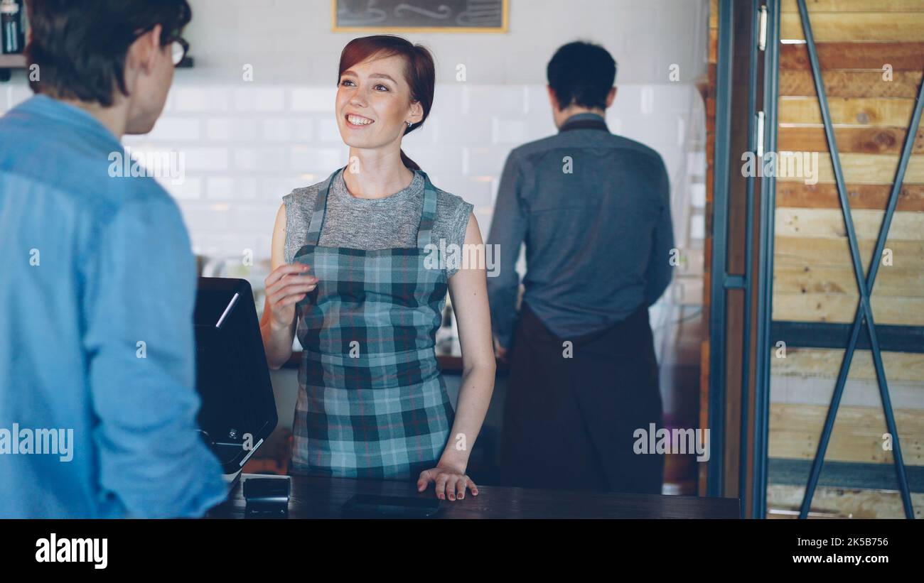 Female employee of coffeehouse is talking to customer and selling ...