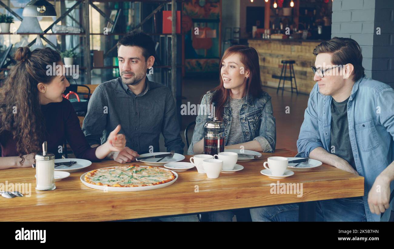 Cheerful young friends are talking and gesturing sharing news while ...