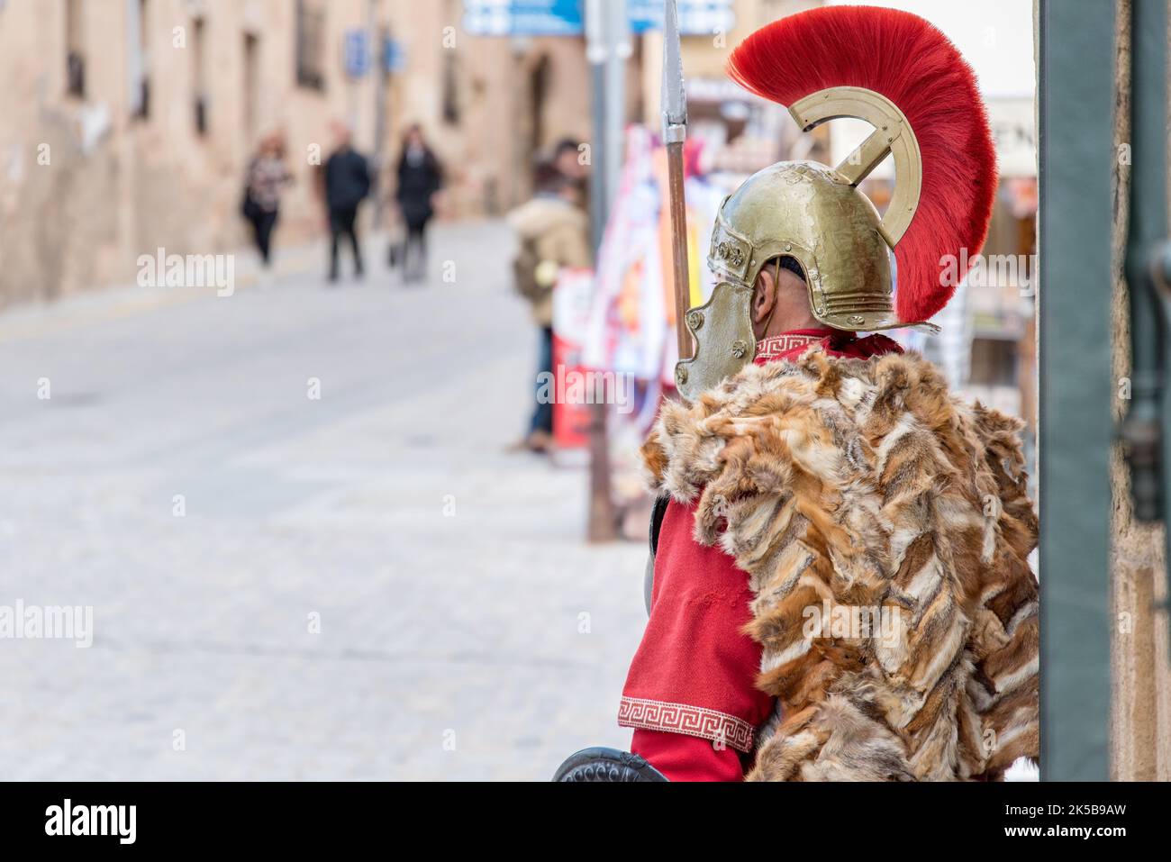 A person wearing Roman gladiator helmet and a long red cloak with a ...