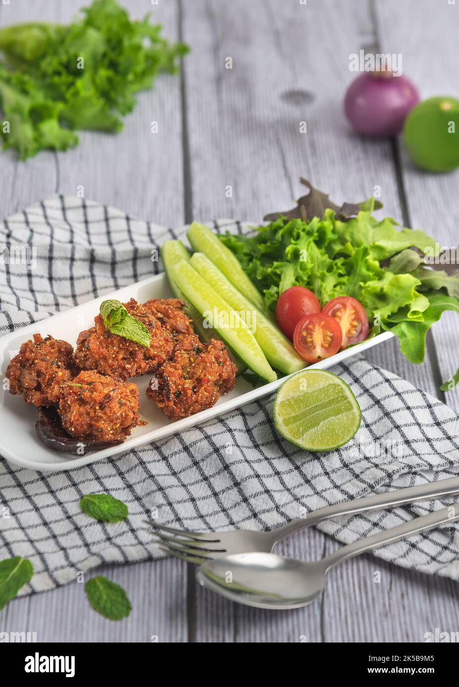 Fried Pork Larb (lab tod) in long plates with vegetable side dishes on ...