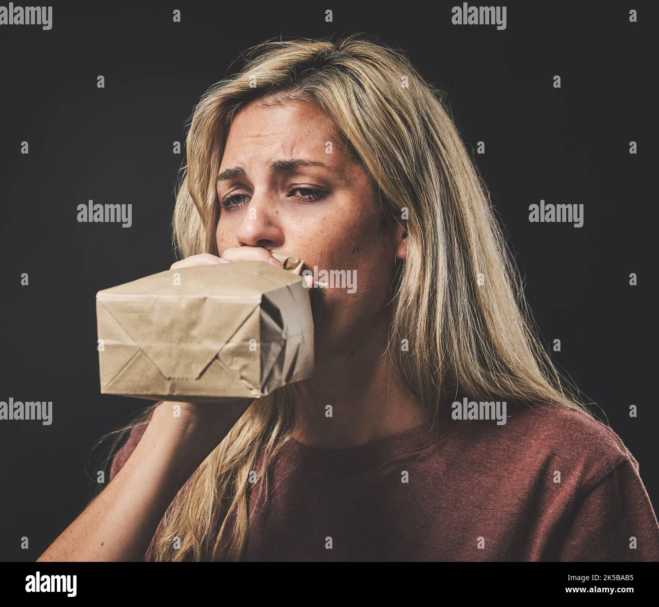 Anxiety, scared woman breathing into paper bag on dark background for ...
