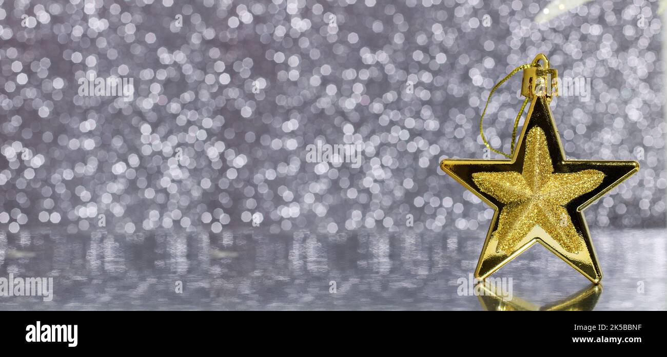 Gold bronze Christmas star on a defocused silver Christmas lights ...