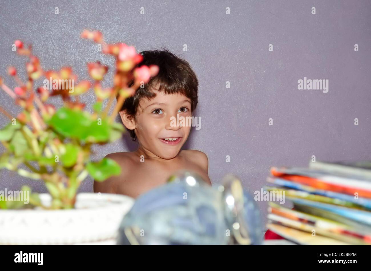 Kid sitting on chair with table against lilac wind television wall ...