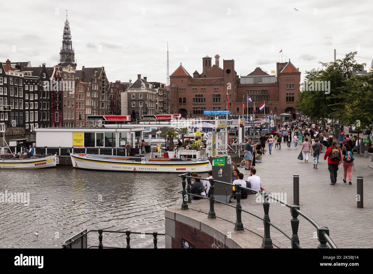 Residents and tourists walk along the canal cruises on the Damrak in ...