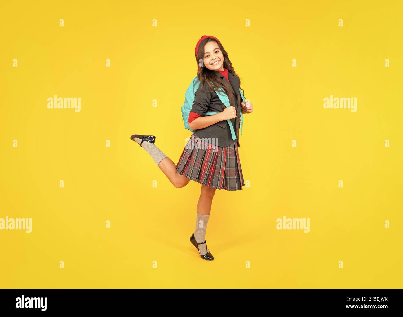 happy kid in school uniform and backpack jump on yellow background ...