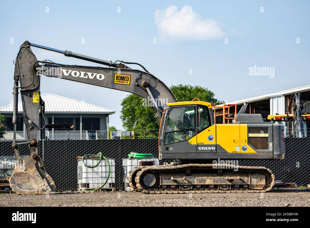 The view of an excavator parked by the fence under the blue sky Stock ...