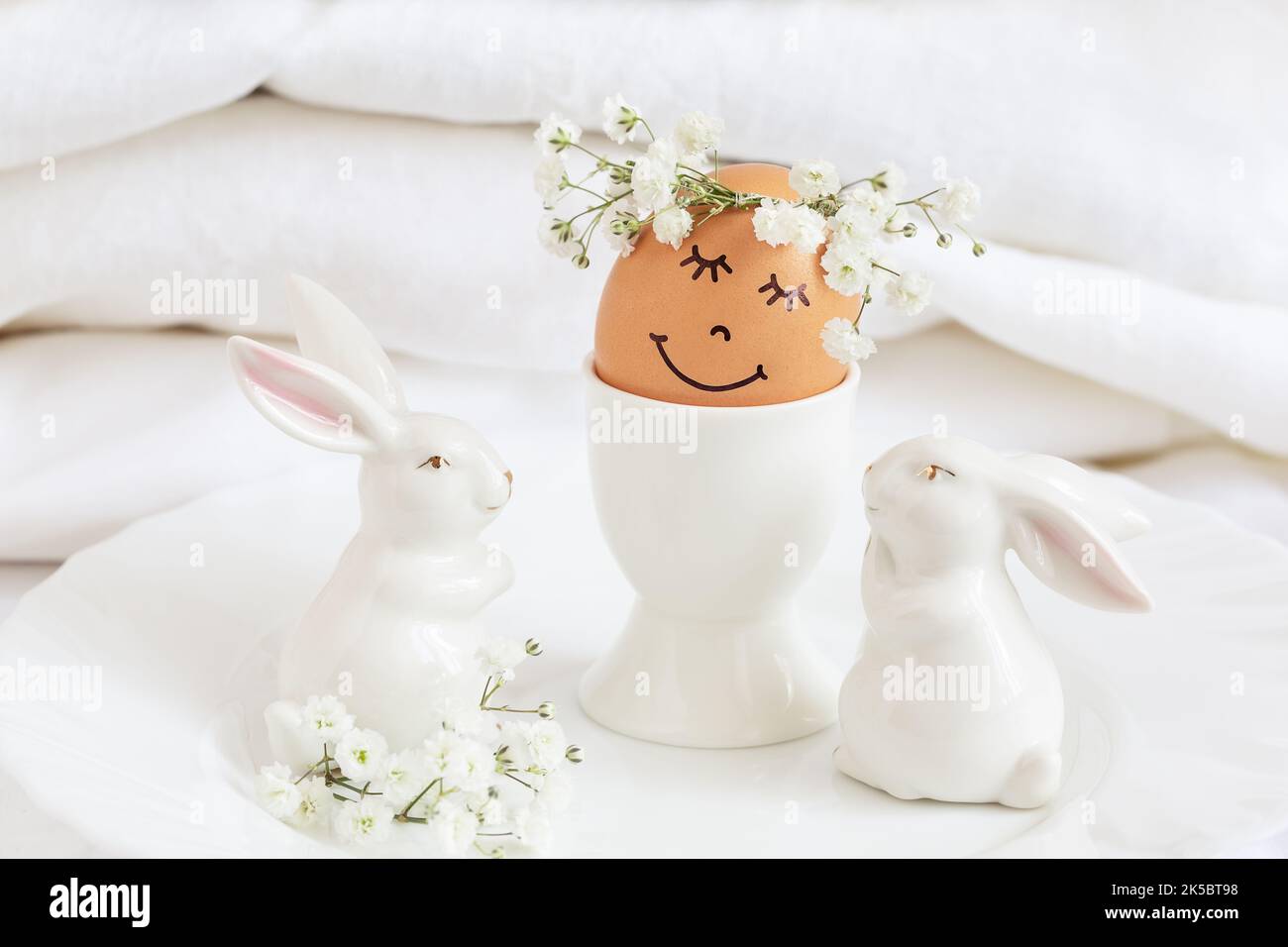 Easter egg with cute face in floral wreath crowns in egg cup with two ...