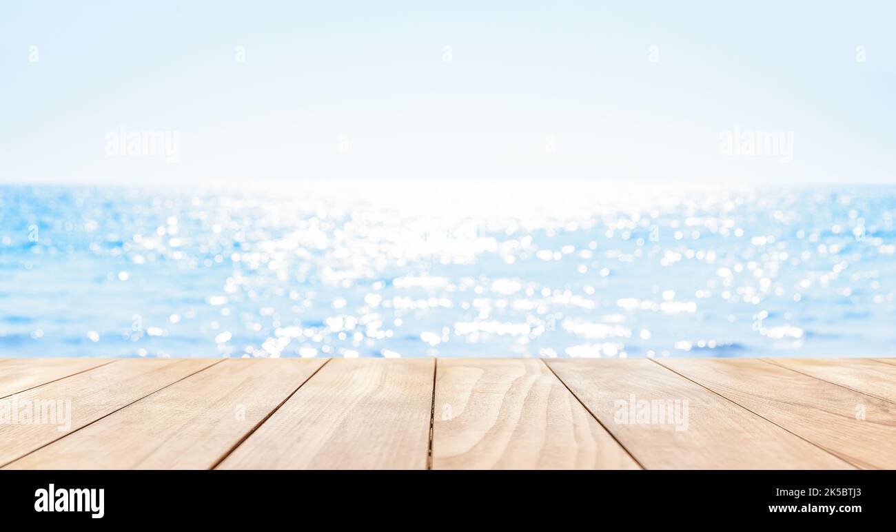 Wooden table top on blue summer sparking sea water with bokeh light ...