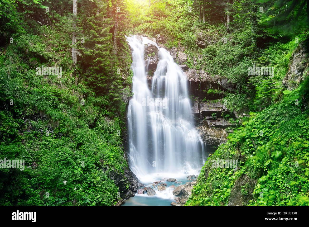 Waterfall cascade on mountain rocks. A mountain waterfall flows over ...