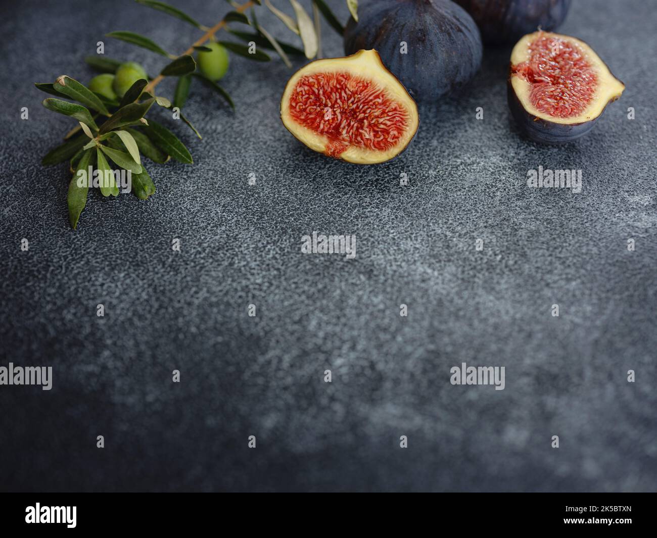 fresh ripe figs fruit and olive branch on dark table. mediterranean ...
