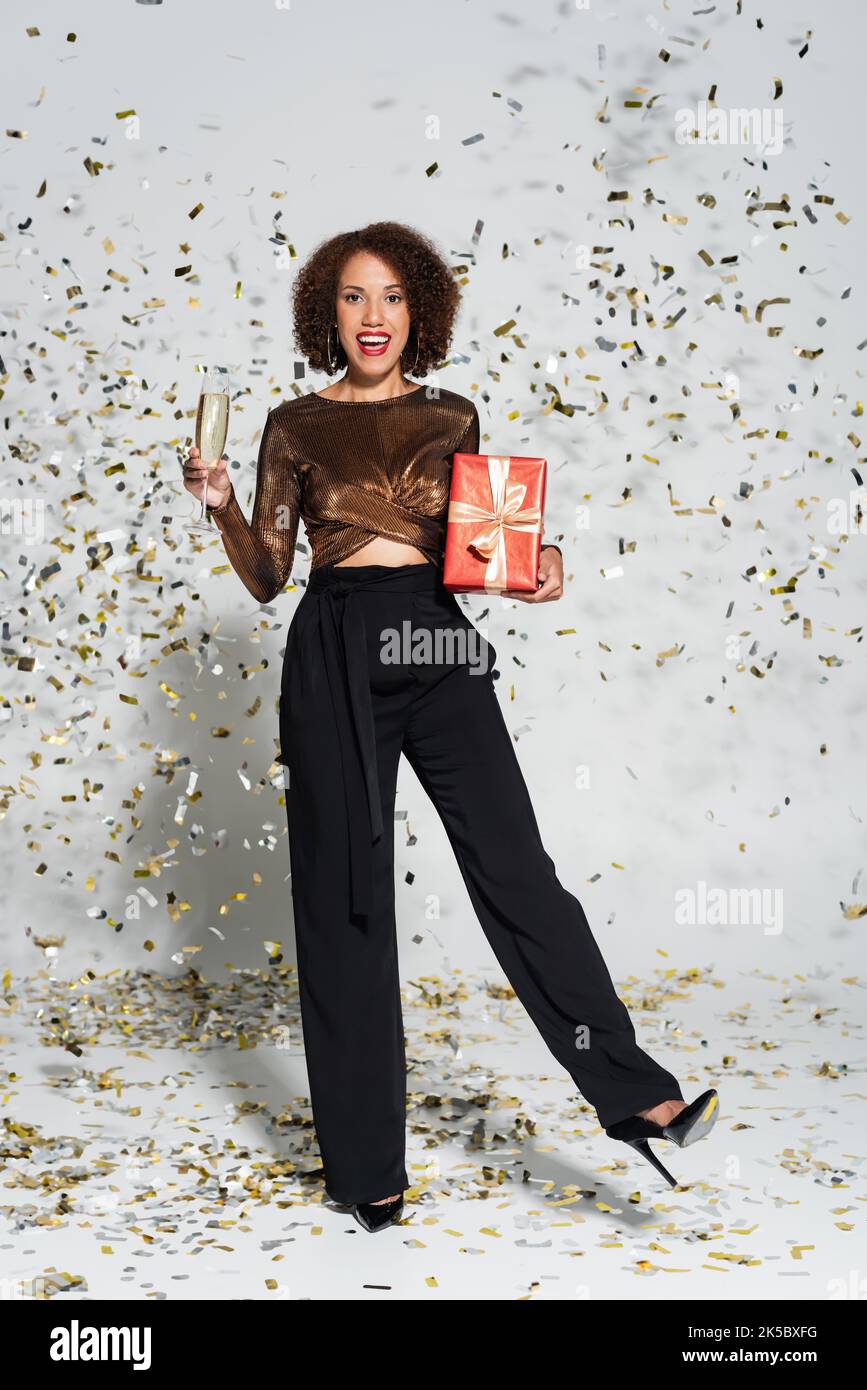 happy and elegant african american woman standing with champagne glass ...