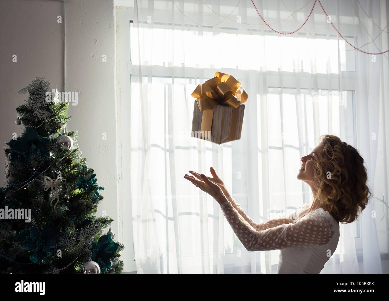 attractive cheerful girl 18 years old throws up gift box against of ...