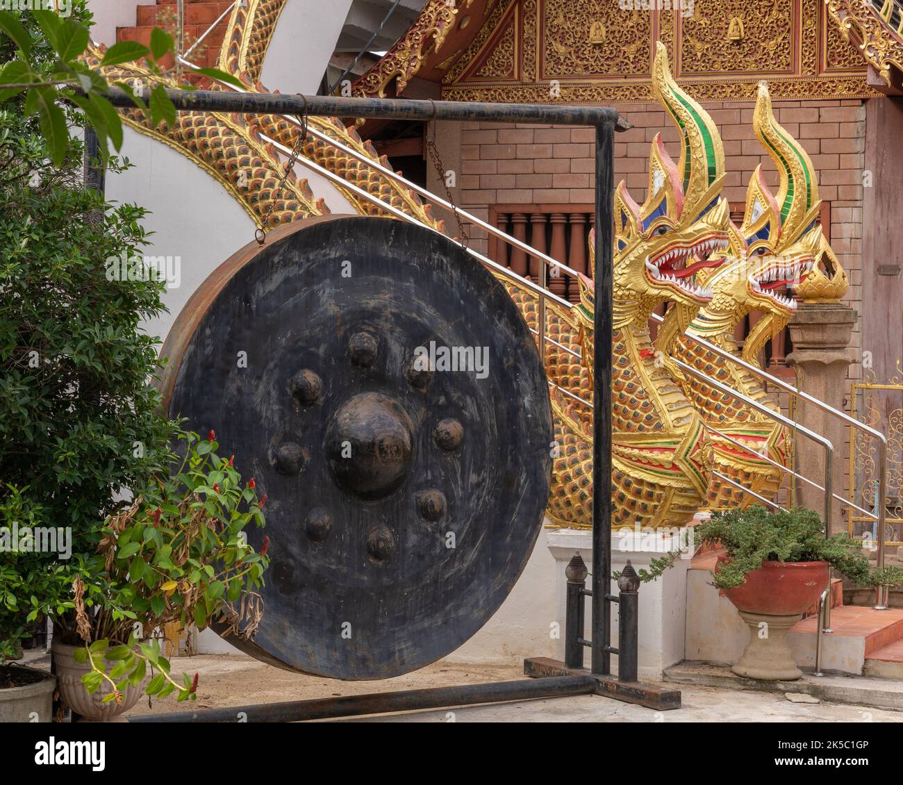 Big black gong hanging in metal frame with golden naga in background at ...