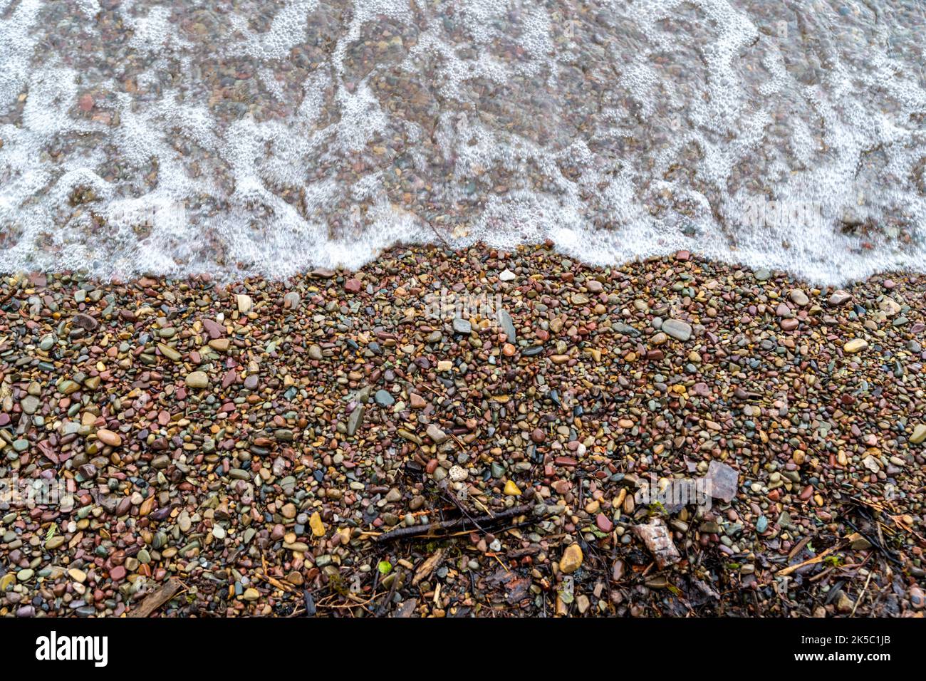 Waves on the rocky shoreline of Lake McDonald in Glacier National Park ...