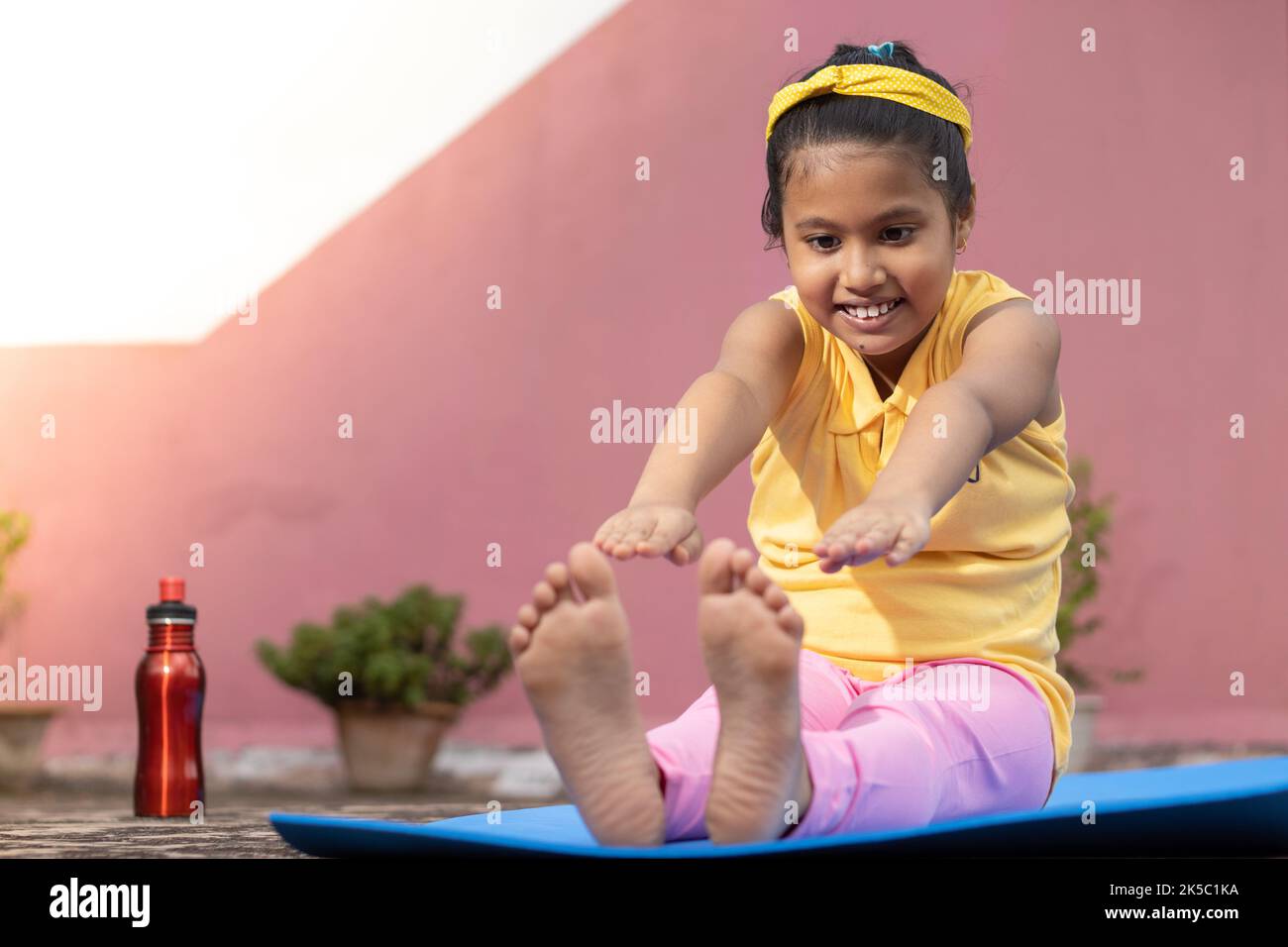 An Indian girl child practicing yoga in smiling face on yoga mat ...