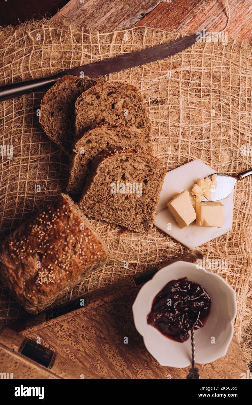 A vertical top view of bread slices, butter, and jam placed on a wooden ...