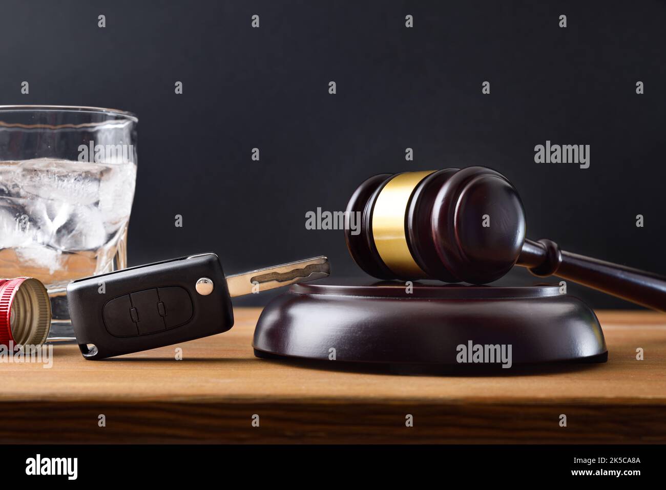 Gavel, car key and glass with alcohol on wooden table and black ...
