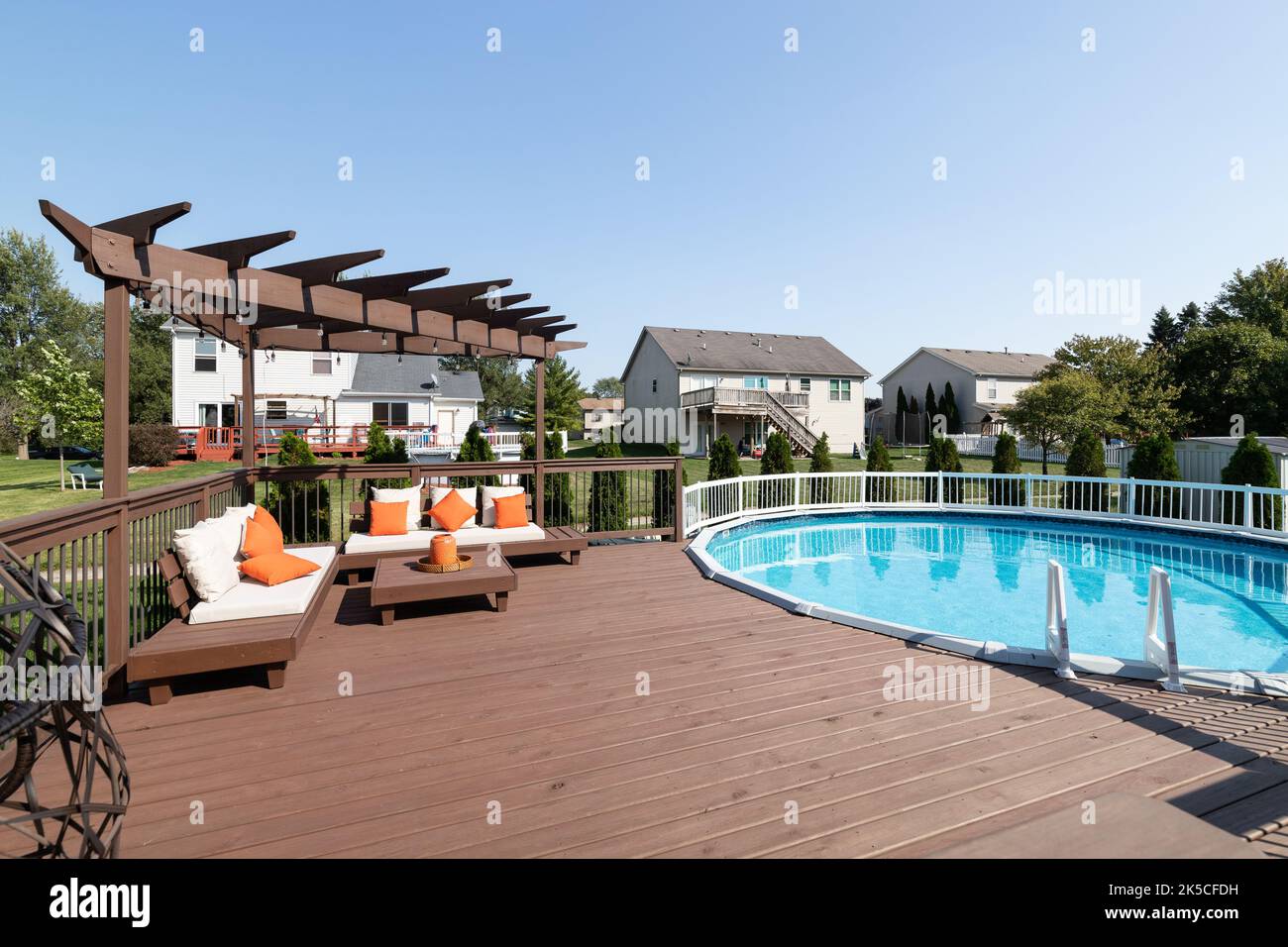 A backyard deck with a pergola over some seating and a large above ...