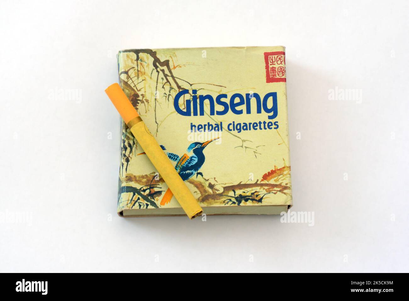 A yellow ginseng herbal cigarette on a box with a white background ...