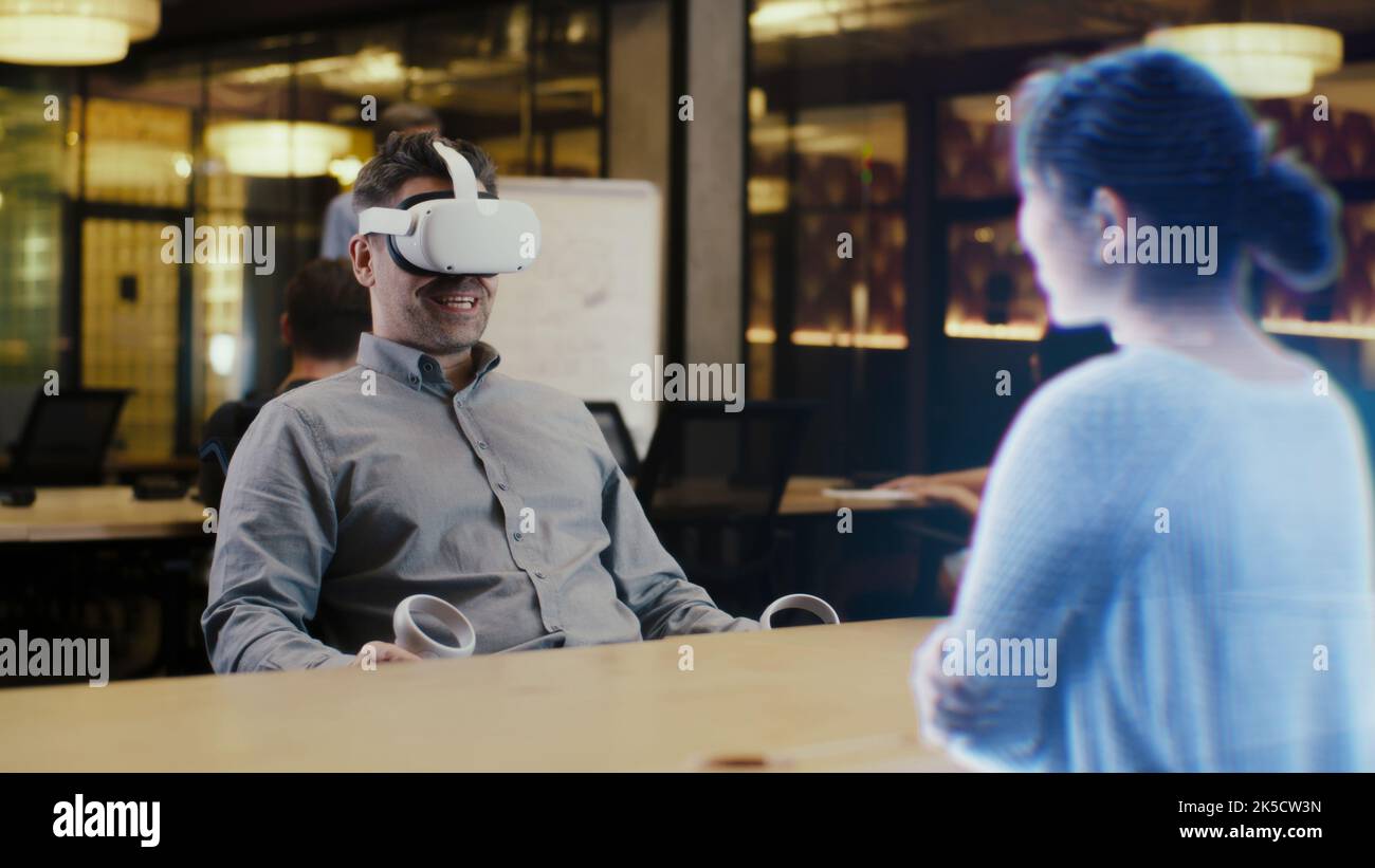 A man with virtual reality headset sits in an office table using ...