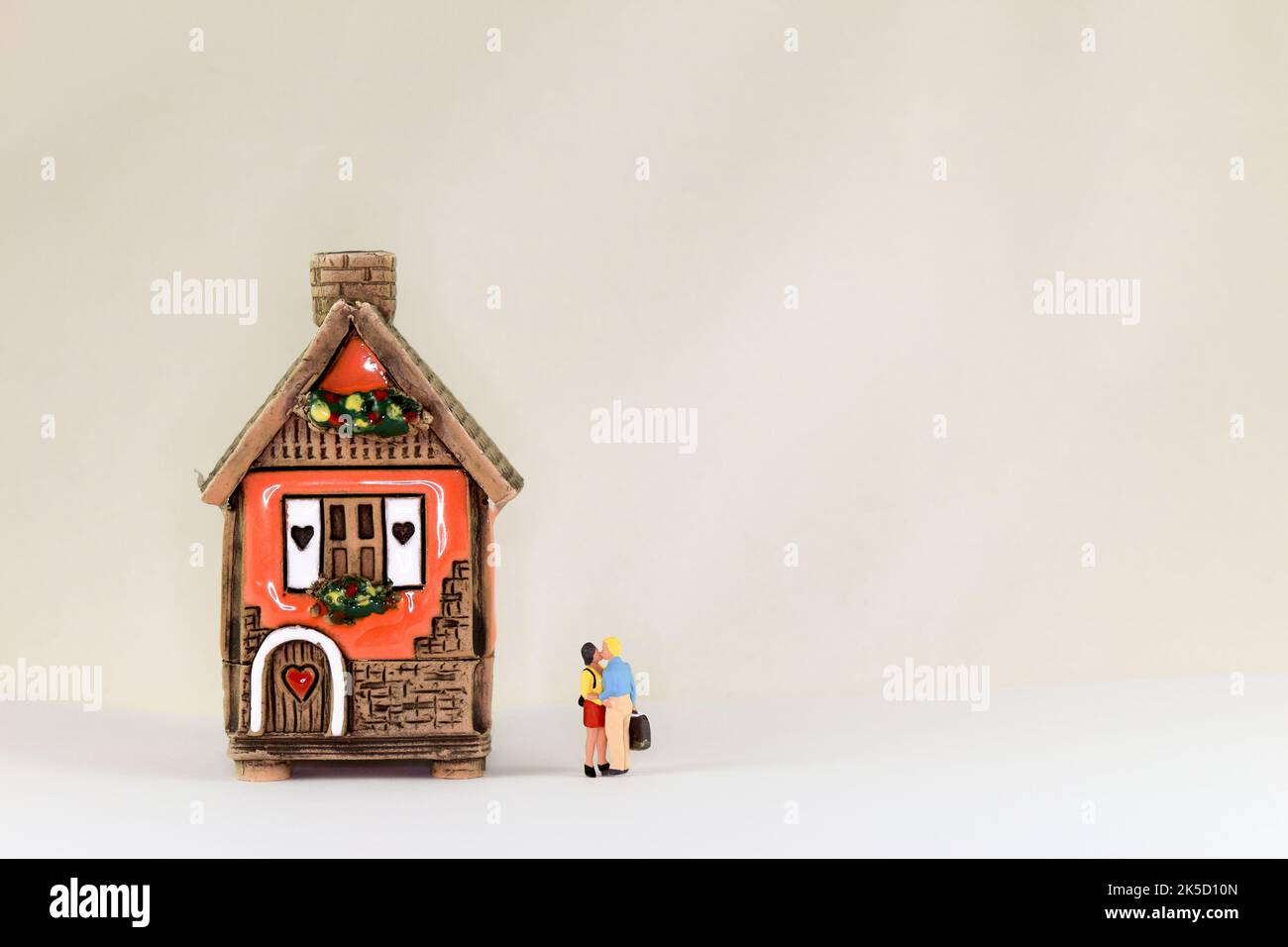 Miniature people an engaged couple kissing near a pretty little house ...