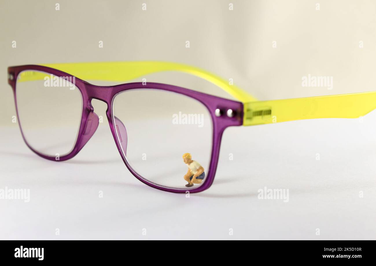 a miniature boy is looking at something behind the lens of glass Stock ...