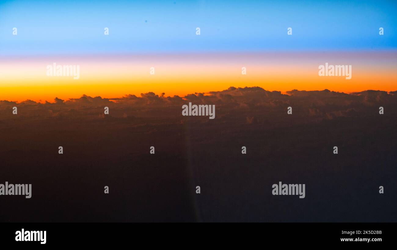 An orbital sunrise illuminates cloud tops over the Pacific Ocean as ...