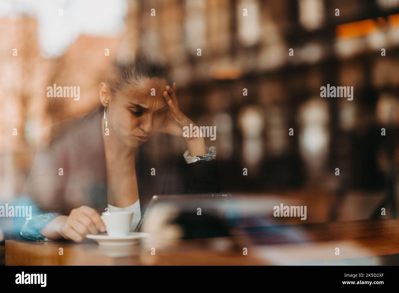 woman in a coffee shop drink coffee viewed through glass with ...