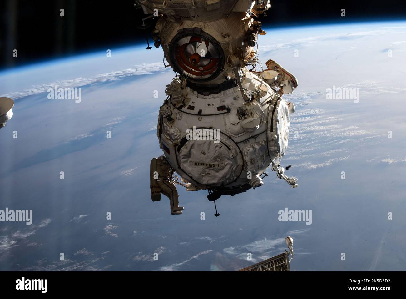 Cosmonauts Pyotr Dubrov (attached to the bottom left portion of the Prichal docking module) and ...