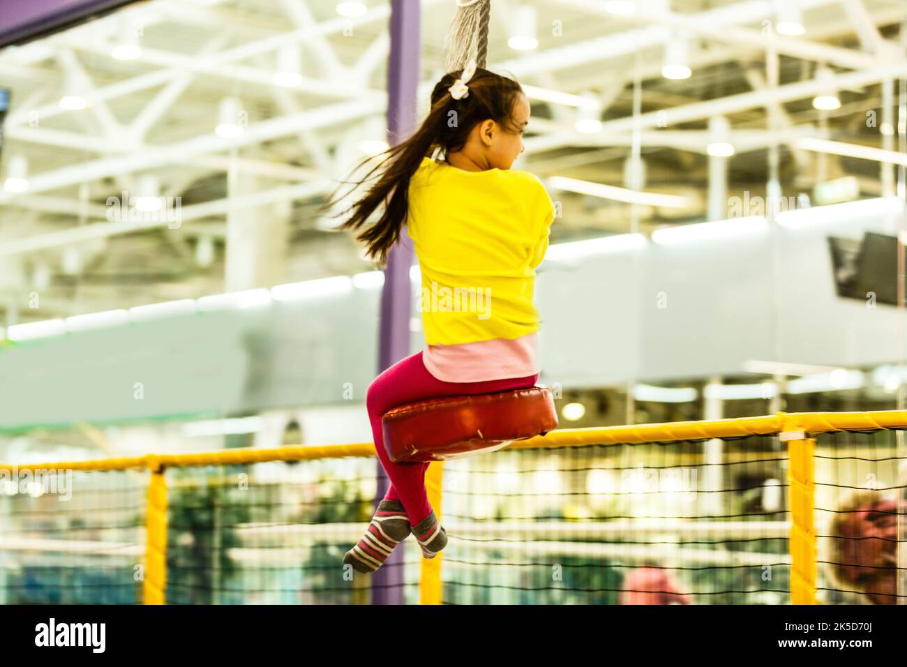 Adorable Little girl laughing happily, riding upside down on a bungee ...