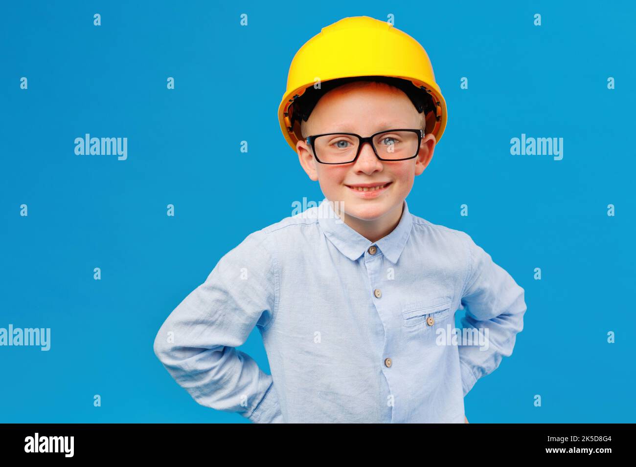 Cute boy construction worker in yellow hard hat standing in indoor ...