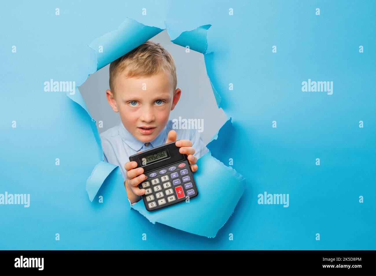 Happy cute businessboy is having fun and holding calculator in hand on ...