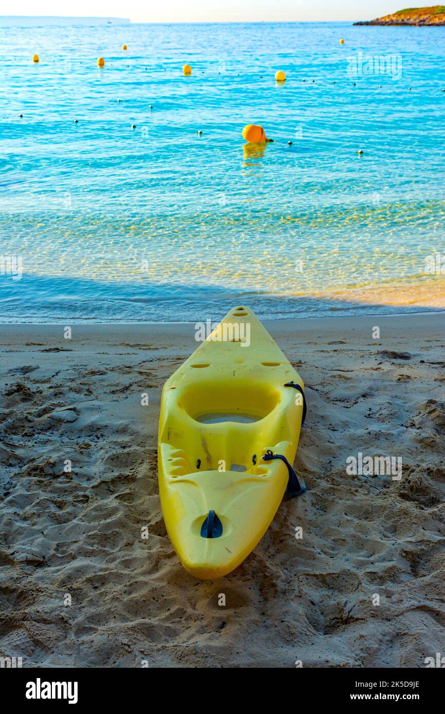 Plastic yellow canoe, in the sand on the beach, in Ses Illetes beach ...