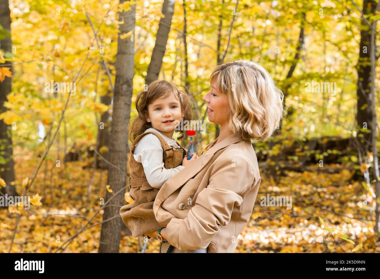 Mother with child in her arms against background of autumn nature ...