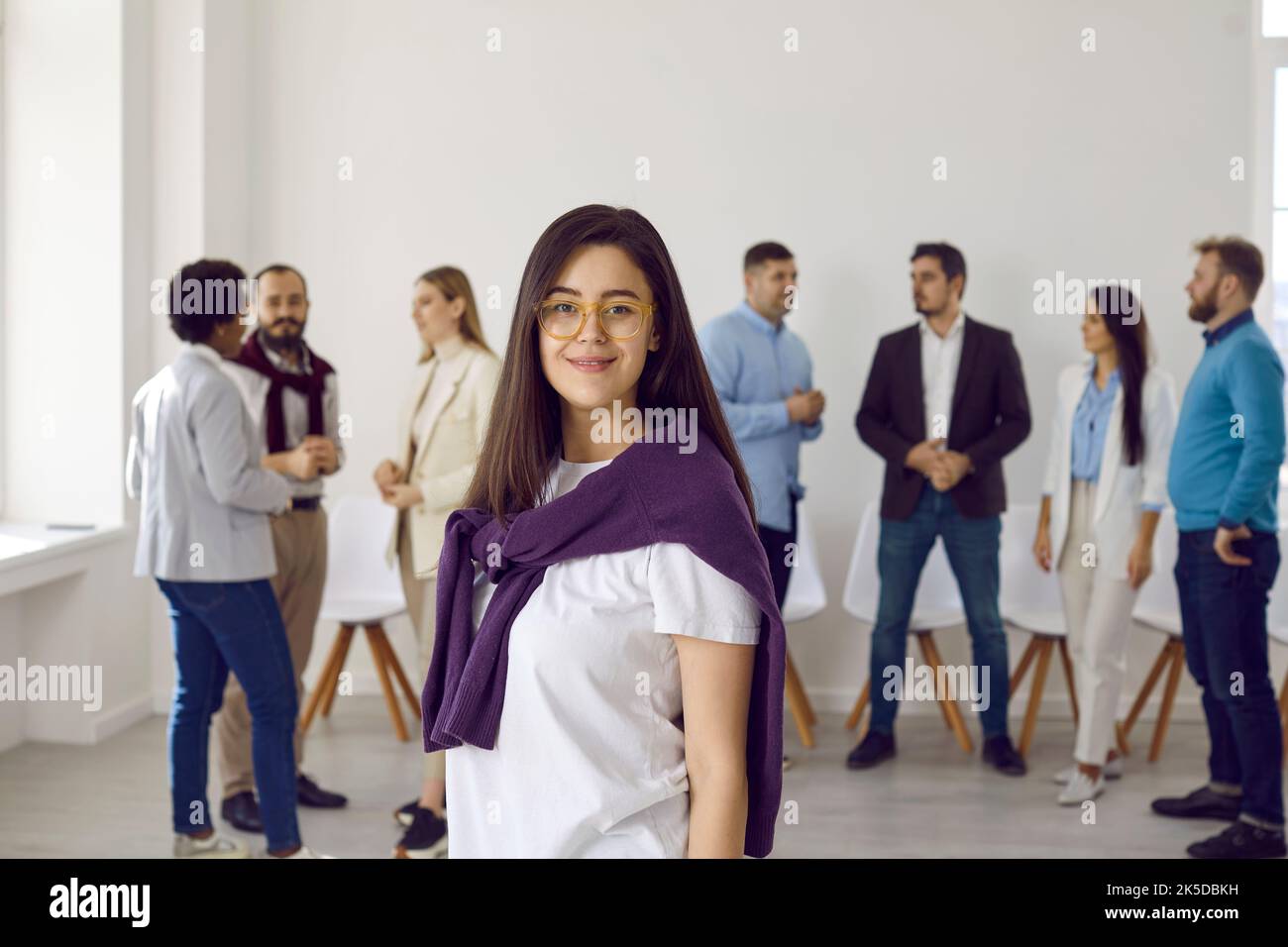 Happy young business woman in glasses standing in office with team of ...