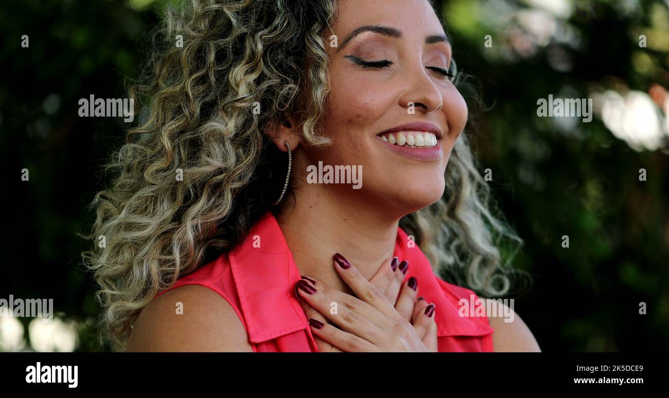 Latina woman putting hand on chest smiling taking a deep breath feeling ...
