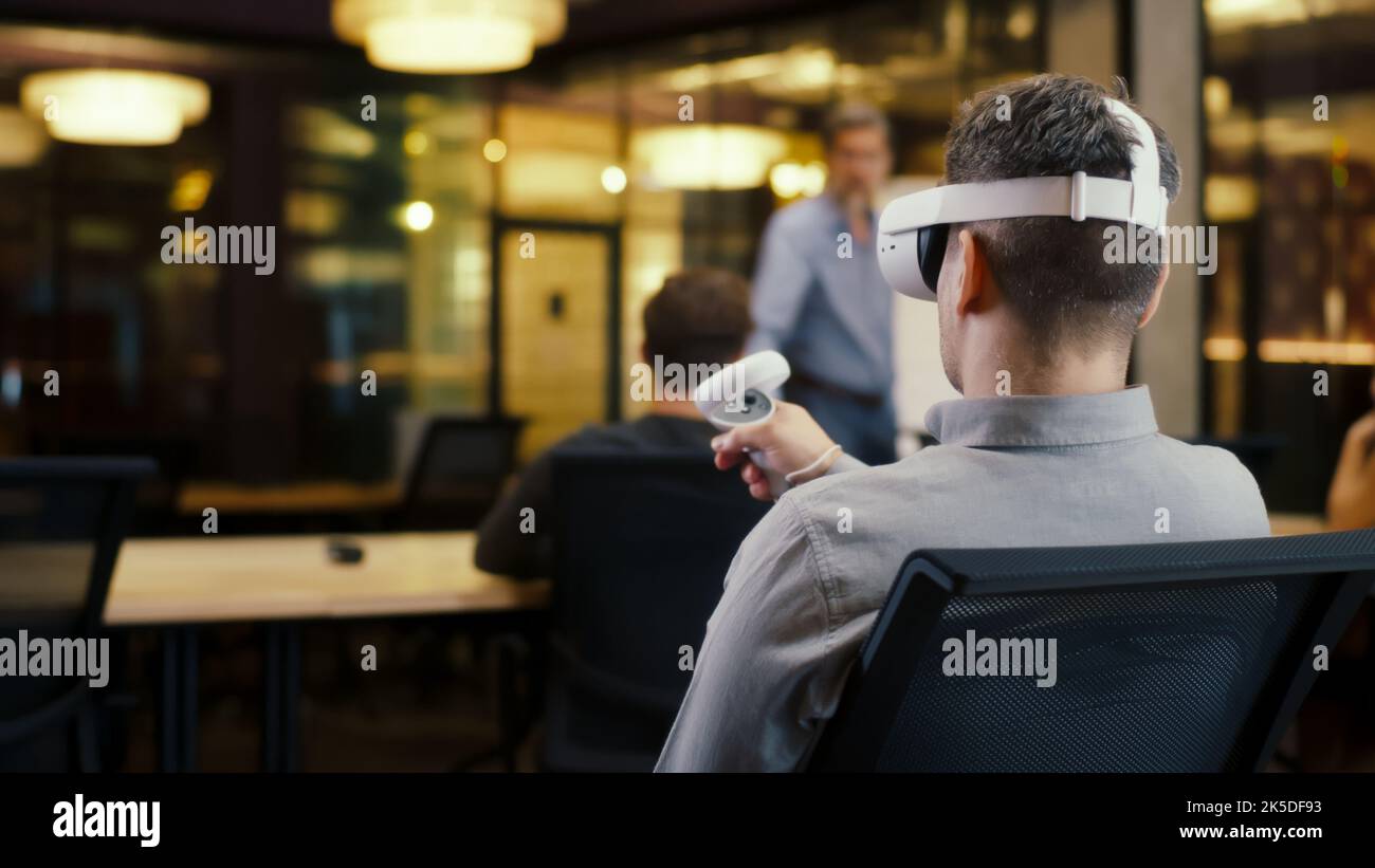 Back view of man wearing VR headset and using wireless controllers ...