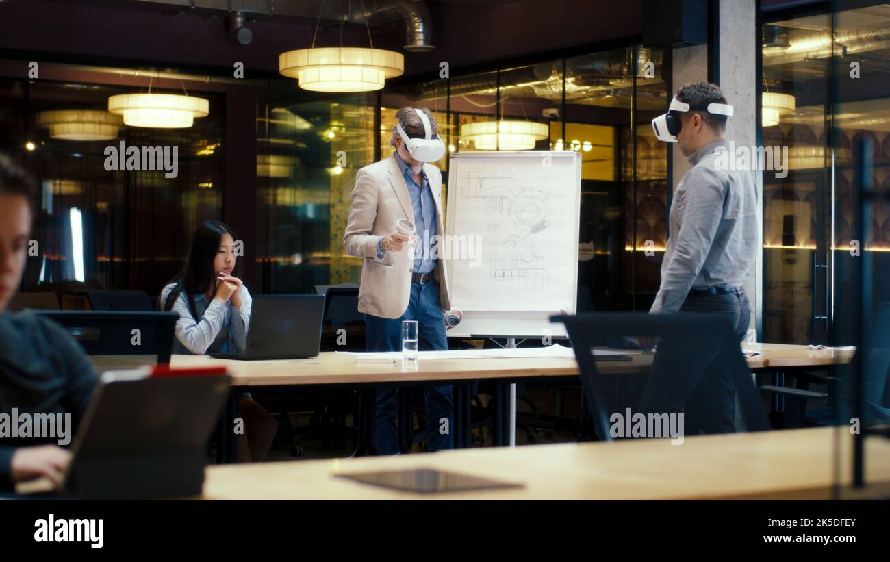 Multi-ethnic engineers in VR headsets, using laptop and wireless ...