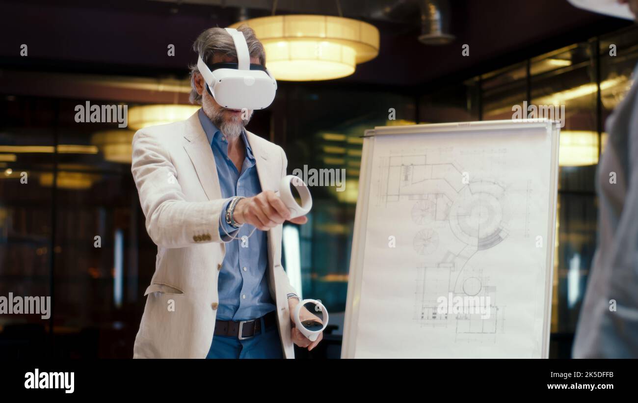 Male engineers using VR headsets and wireless controllers, looking at ...