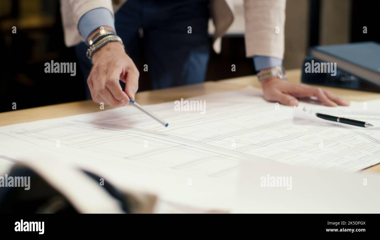 Close-up of engineers team studying blueprints and papers, discussing ...