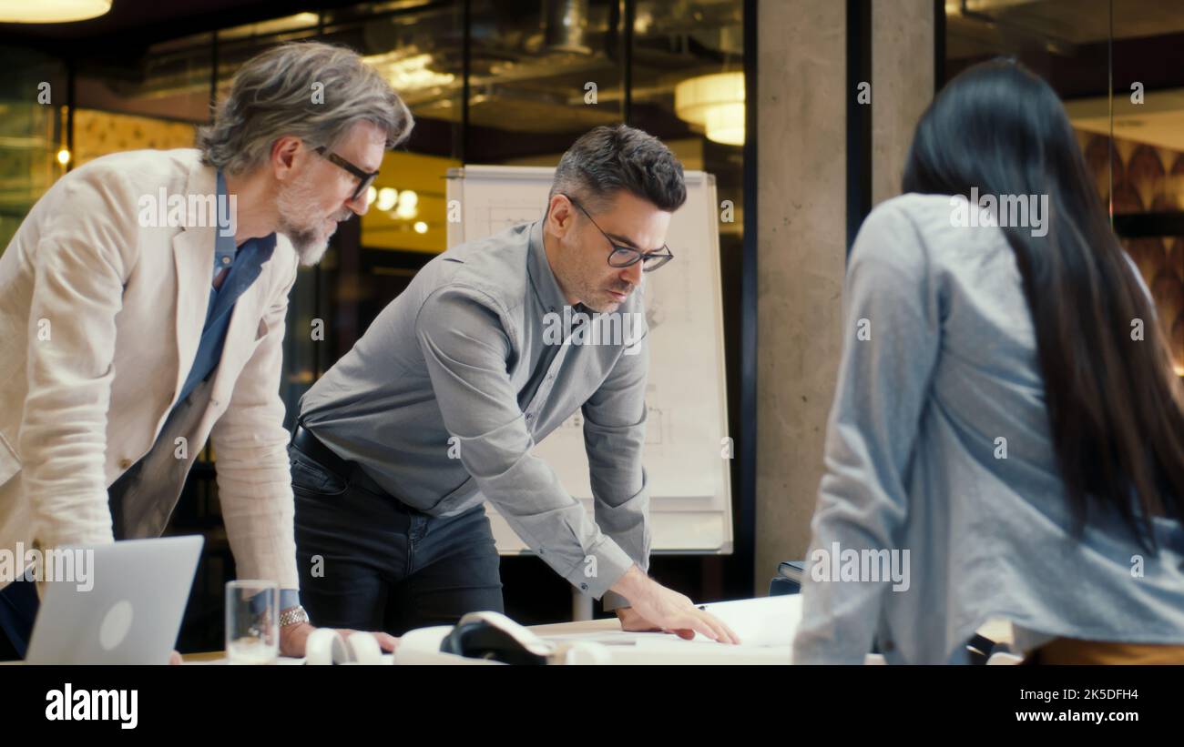 Diverse team of office workers looking through papers, discussing ...