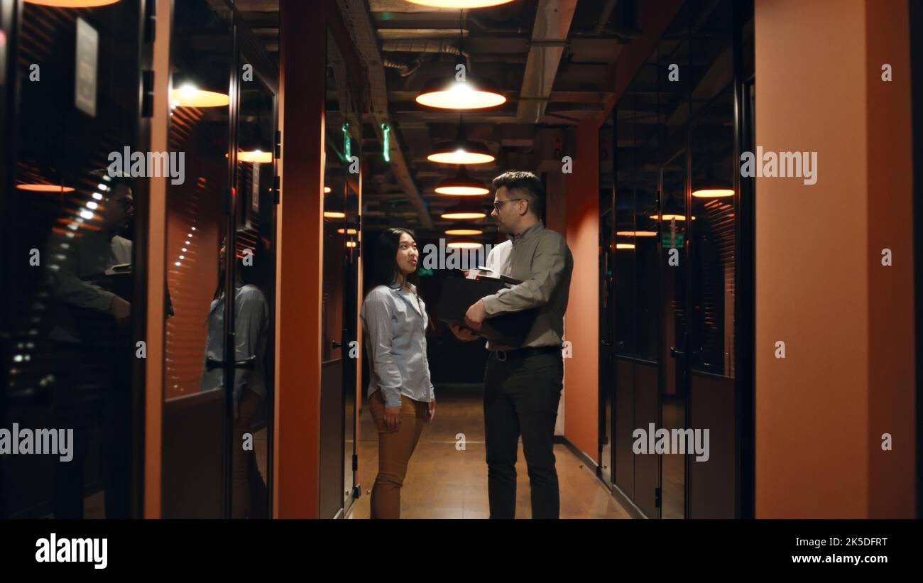 Fired upset worker walking down in office corridor, holding box with ...