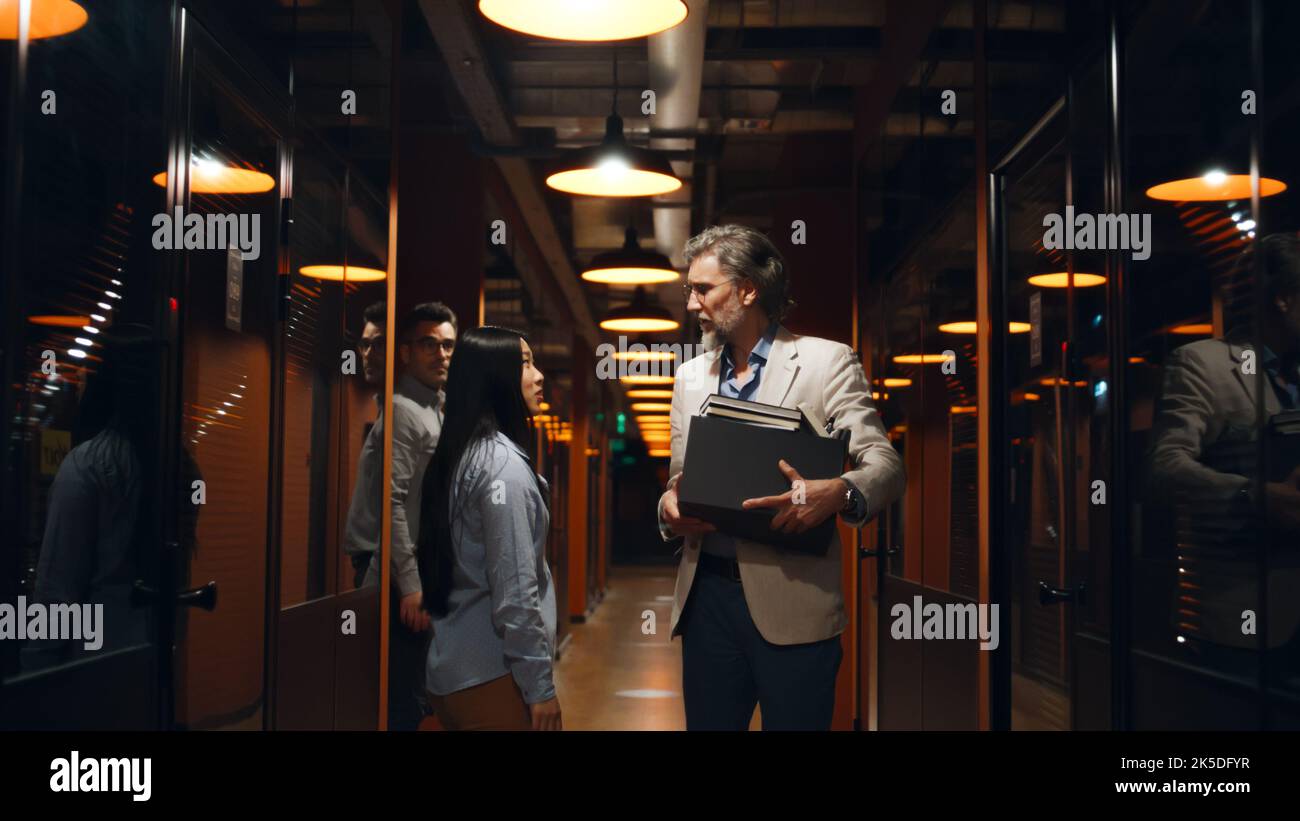 Fired male worker in suit standing in office corridor, holding box with ...