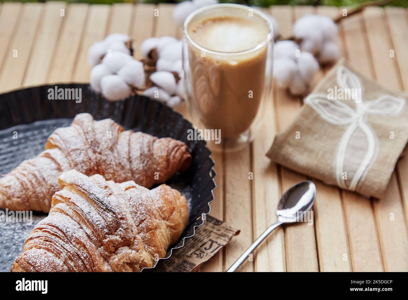 French fresh croissants, cup of latte and cotton at the terrace. Pastel ...